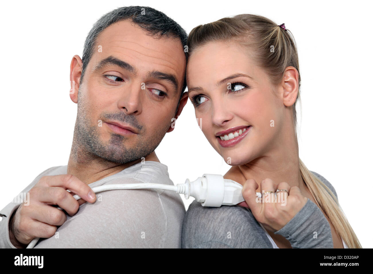 Couple stood back-to-back holding electrical cable Stock Photo - Alamy