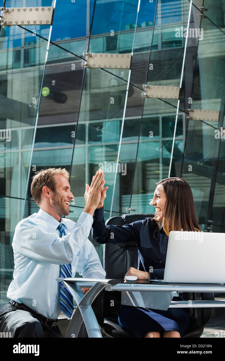 Caucasian business people high fiving at desk Stock Photo - Alamy