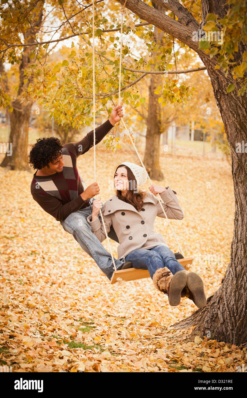 Couple playing on swing in autumn leaves Stock Photo - Alamy