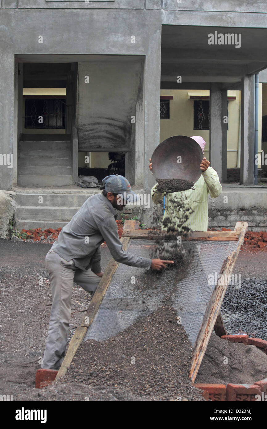 Workers sifting sand in metal mesh for construction Stock Photo - Alamy