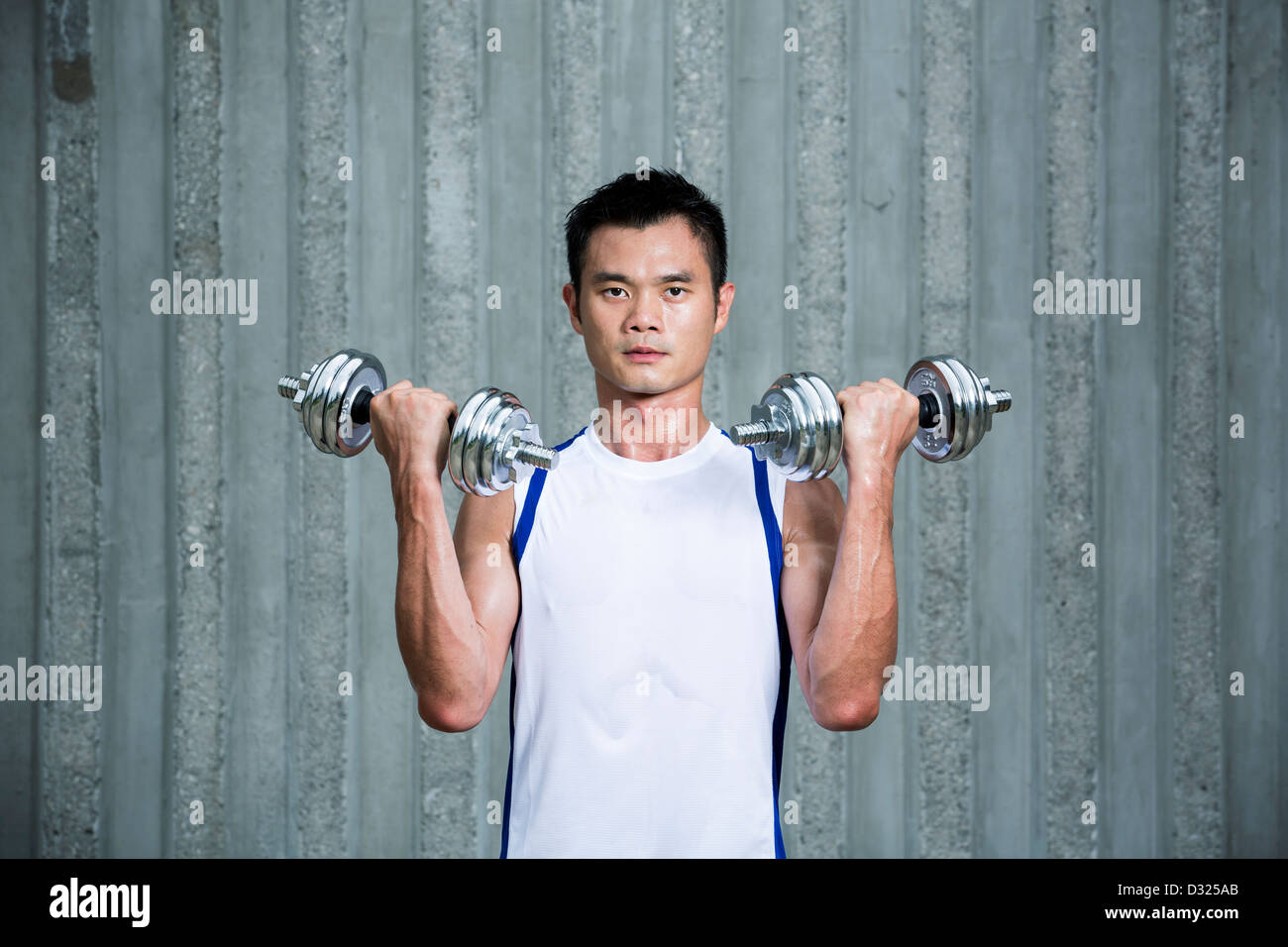 Athletic Young Chinese man exercising with dumbbells. Muscular Asian ...