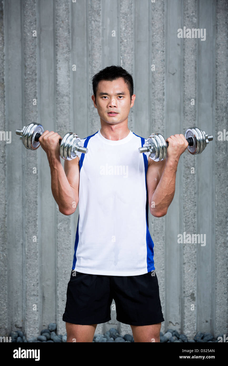 Athletic Young Chinese man exercising with dumbbells. Muscular Asian ...