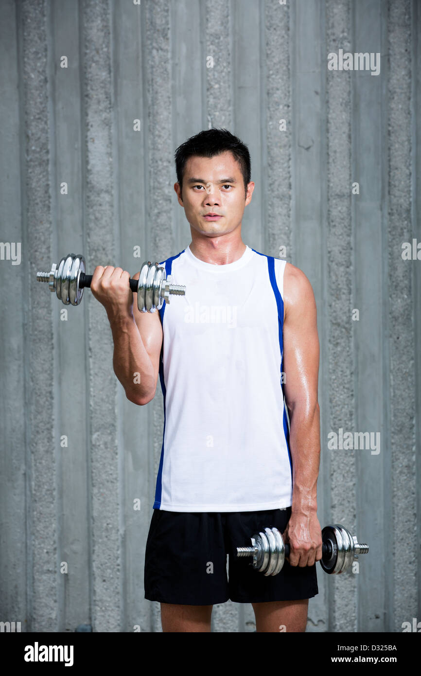Athletic Young Chinese man exercising with dumbbells. Muscular Asian ...