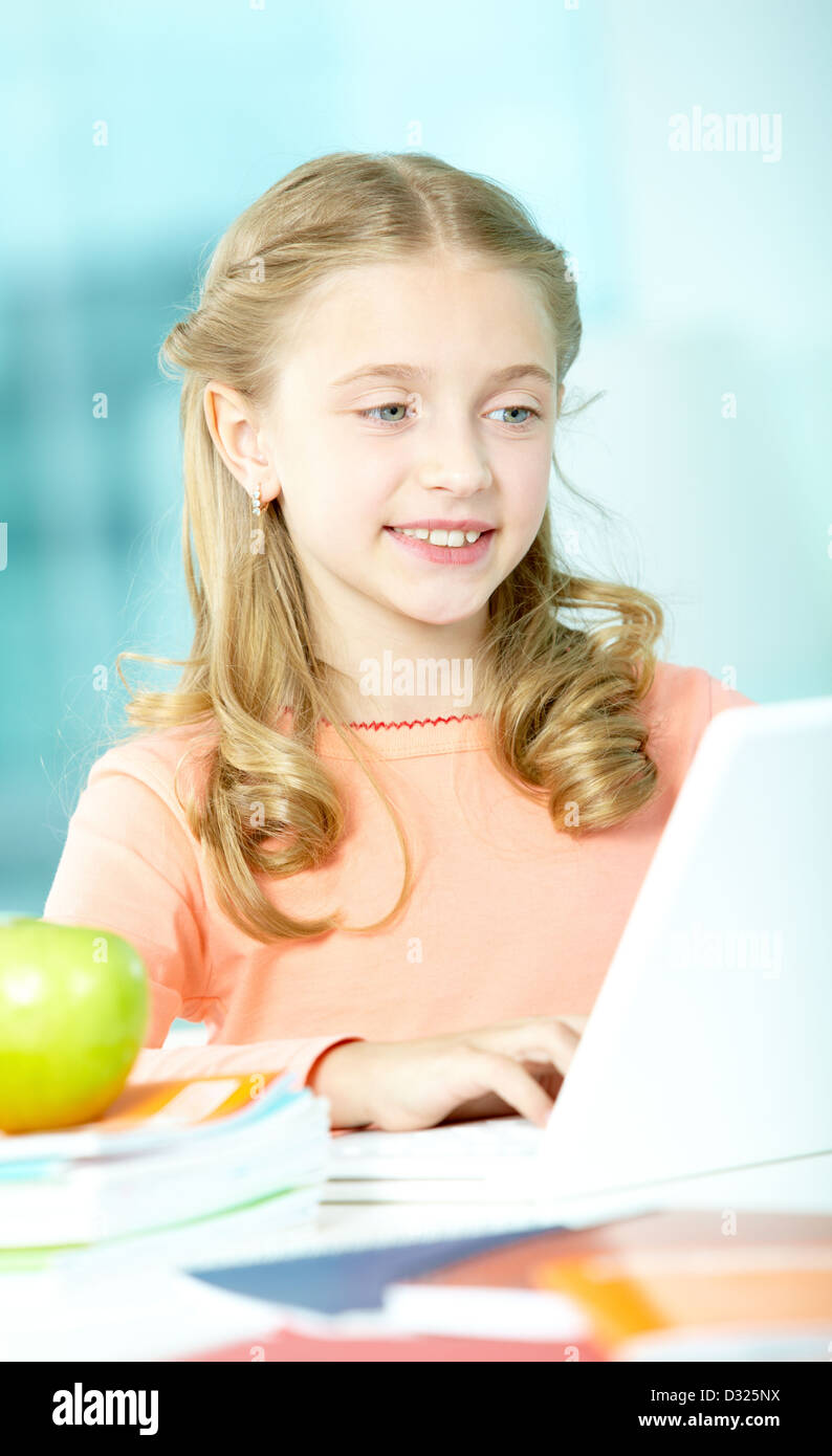 Portrait of smart schoolgirl sitting in classroom and typing Stock ...