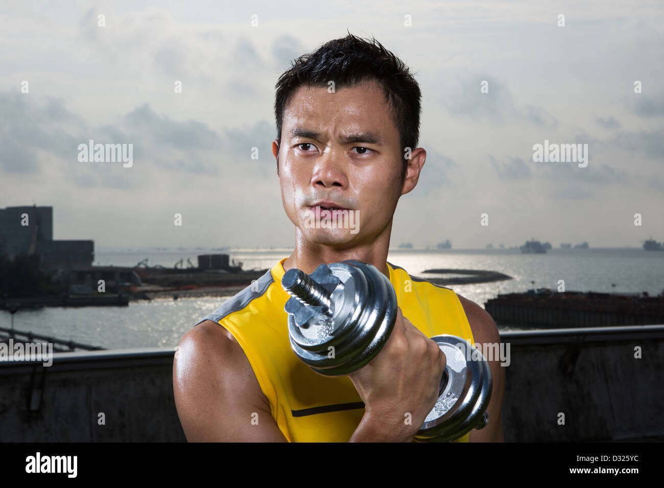 Athletic Young Chinese man exercising with dumbbells. Muscular Asian ...
