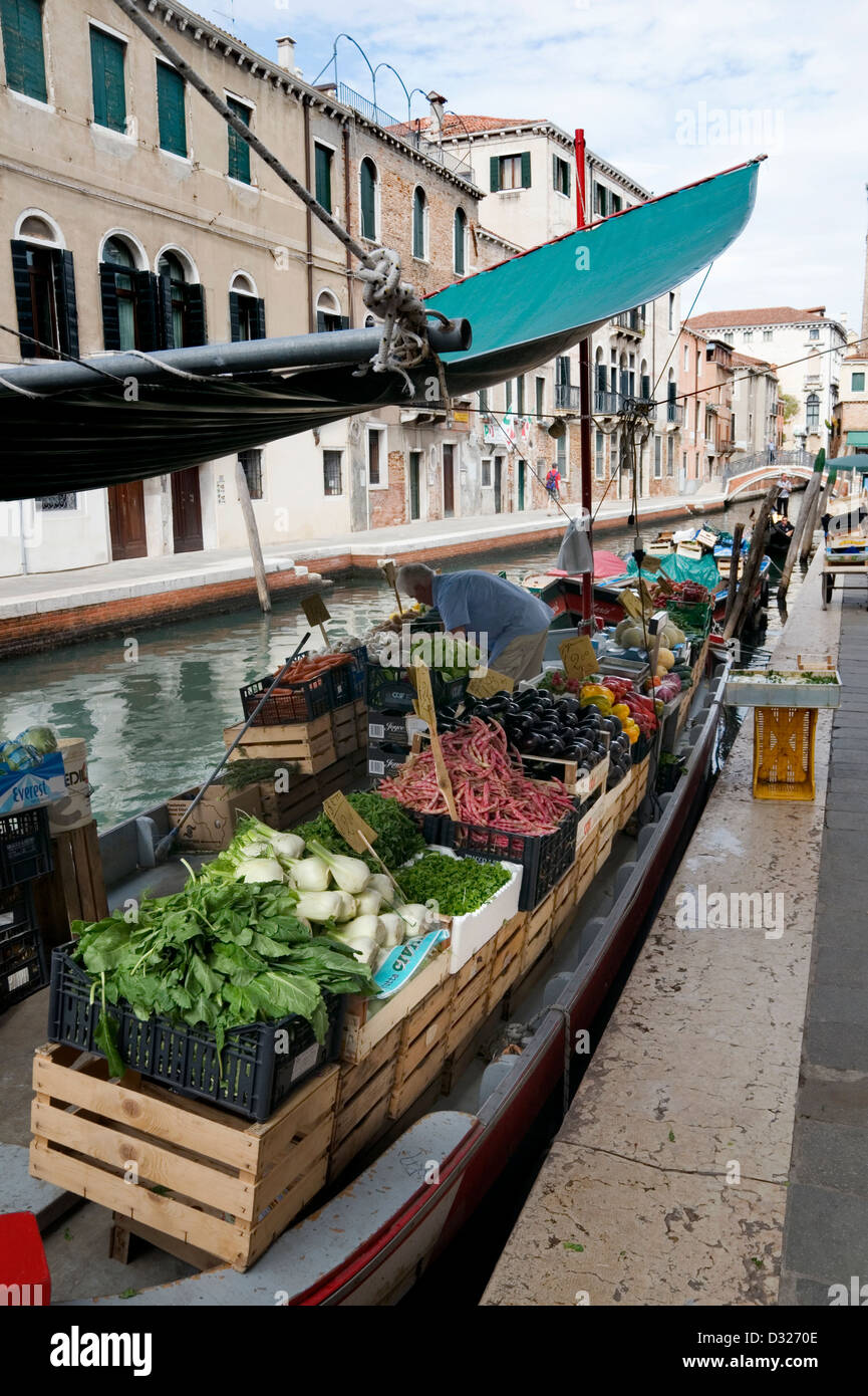 A fruit and vegetable seller on a boat on Rio De San Barnaba alongside ...