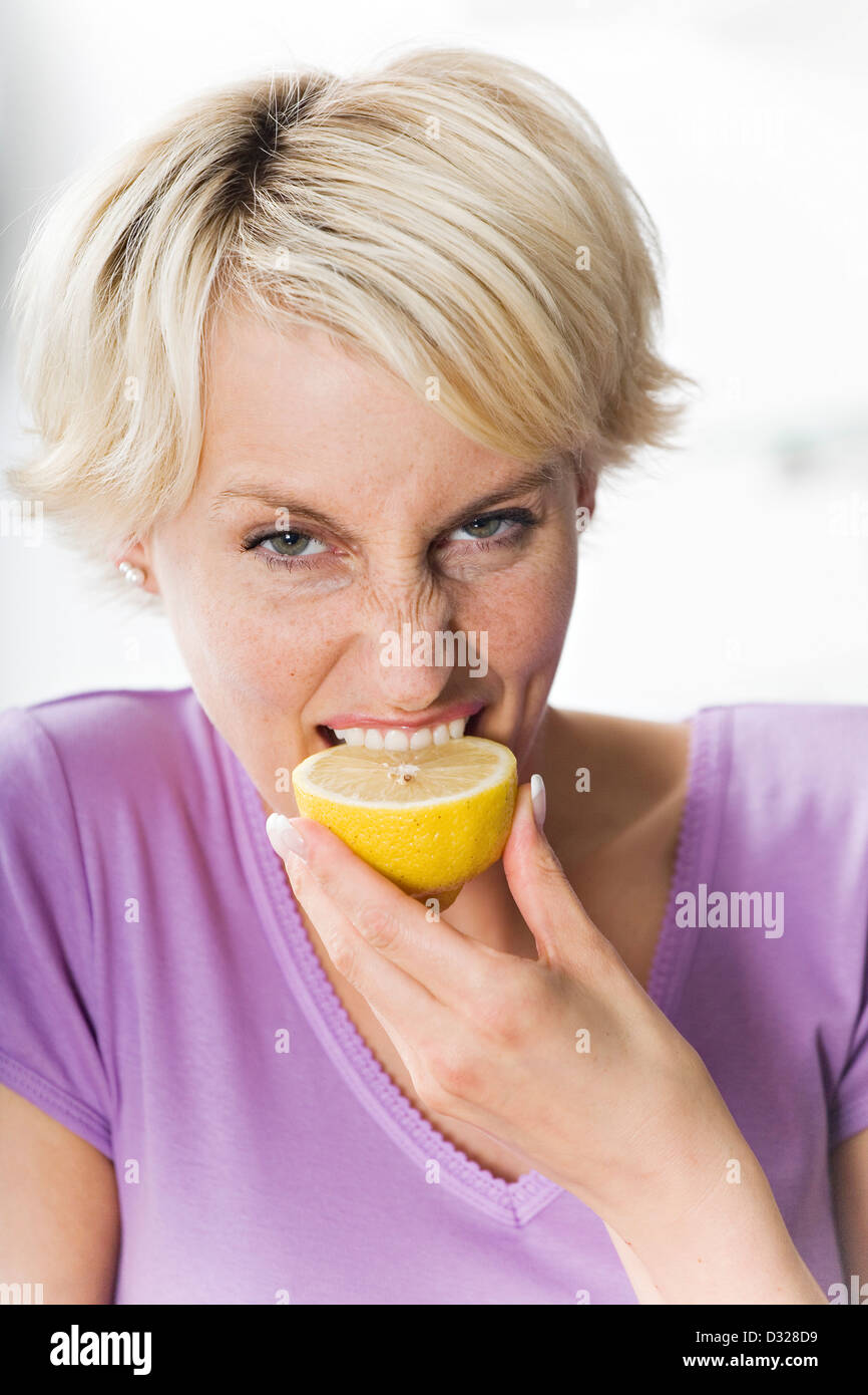Woman biting into a lemon Stock Photo - Alamy