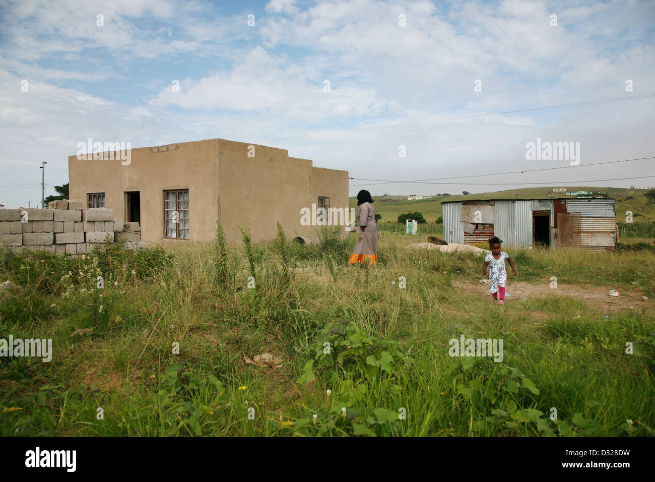 A family lives in a tin shack while their brick house is being build in ...