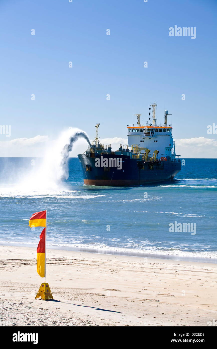 A large sand dredging ship sprays a huge water spout from its water ...