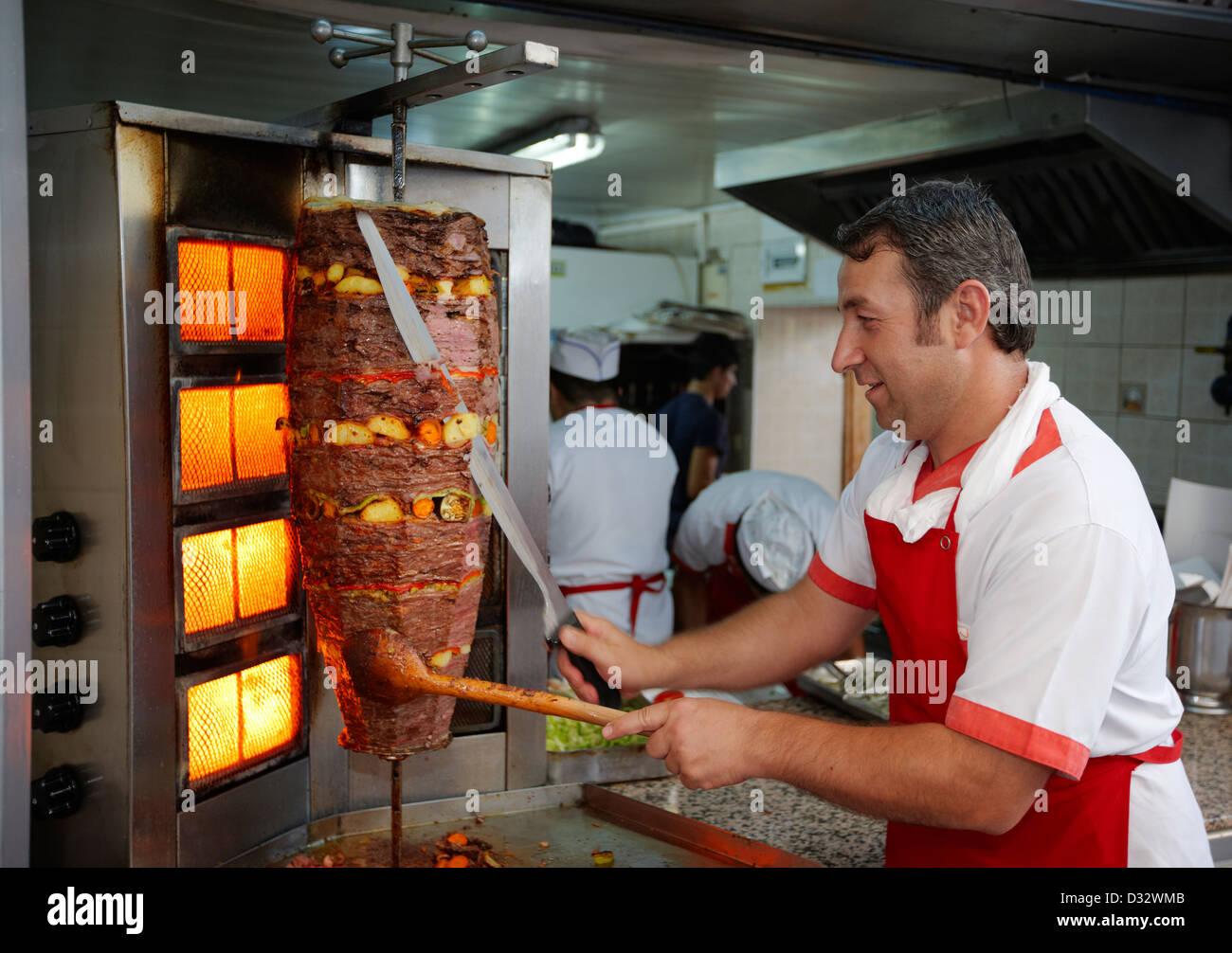 Chef slicing off traditional doner kebab (shawarma) from a rotating ...