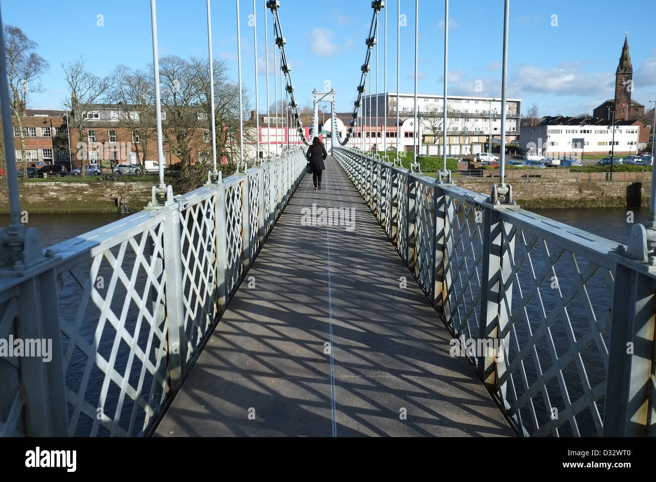 A woman in red scarf walks across the River Nith suspension bridge ...