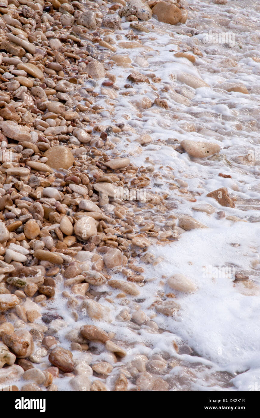 pebble beach with sea encroaching, ripples, foam, gentle tide washing ...