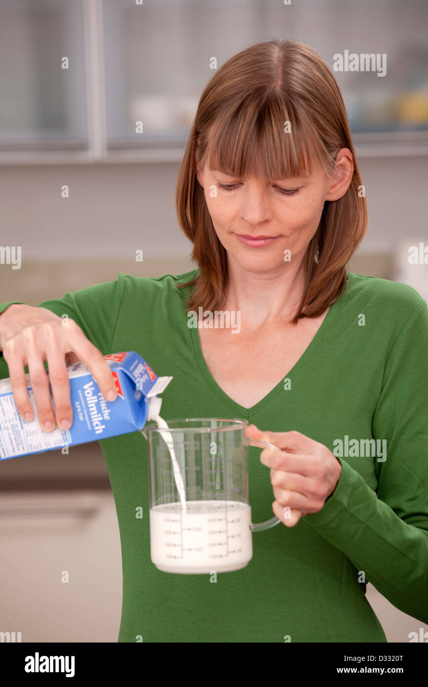Woman pouring milk into a beaker Stock Photo - Alamy