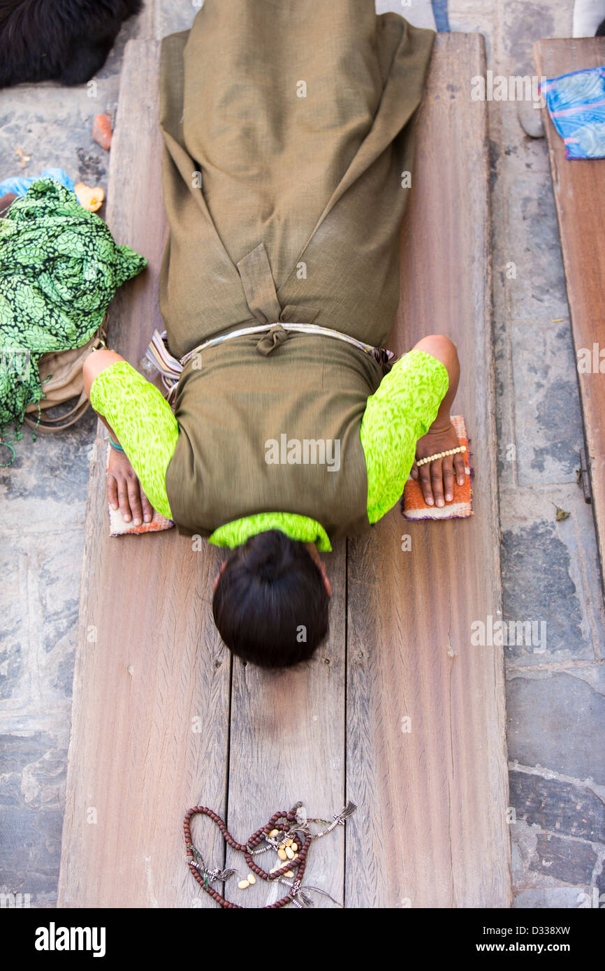 A woman prostrating herself at the Boudanath Stupa, is one of the ...