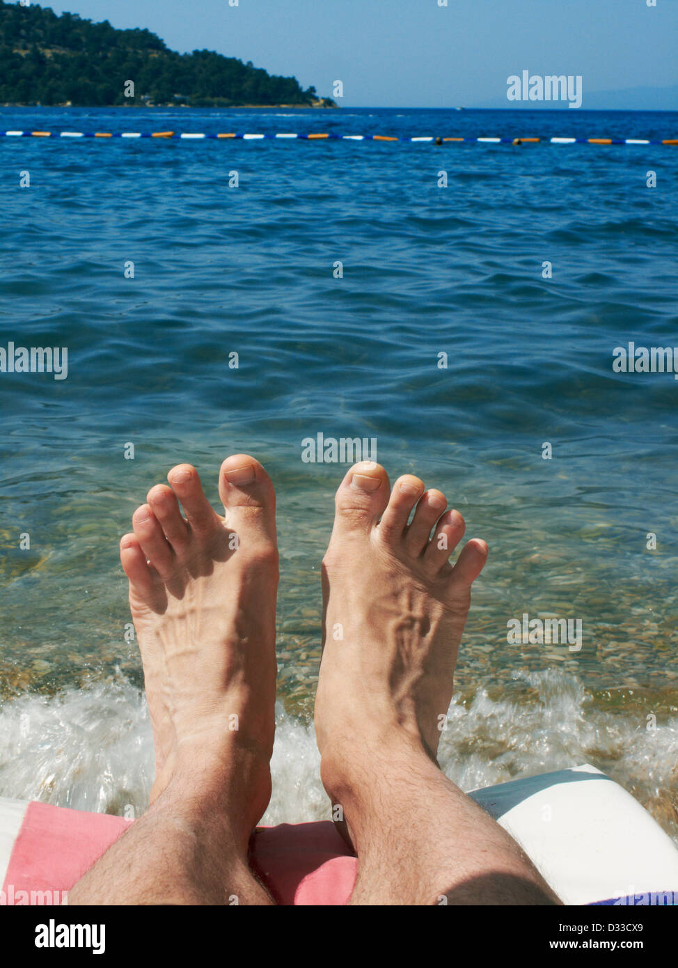 Man's legs and feet on a beach chair with a sea view. Torba village ...