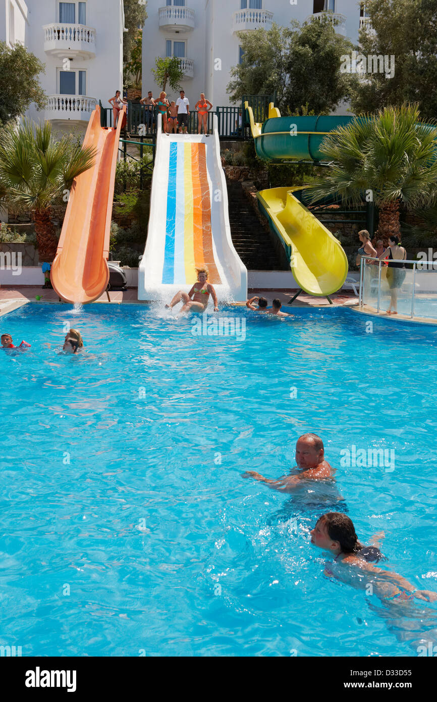 Tourists swimming in a pool with water slides at Caliente Bodrum Resort ...