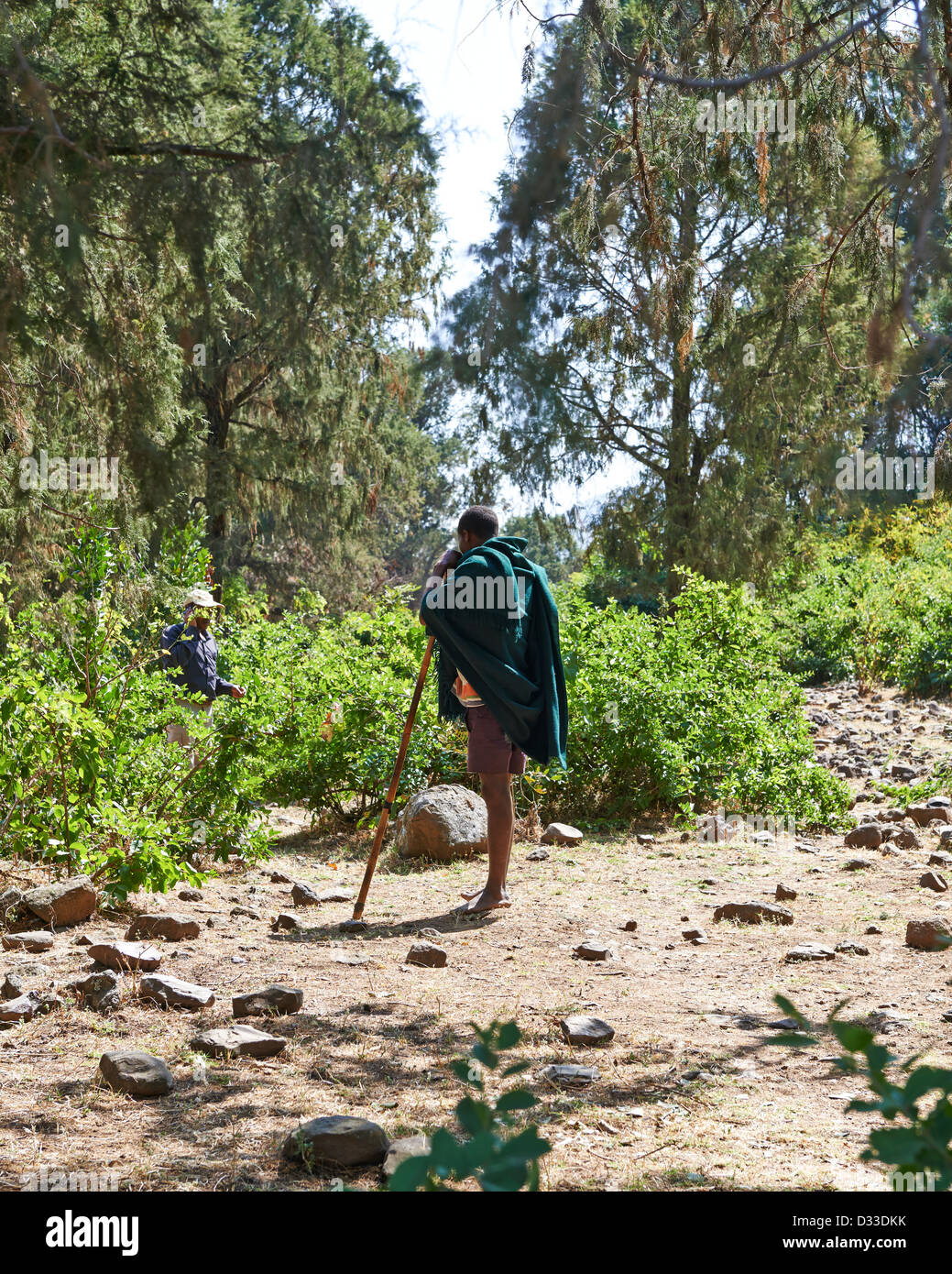 A local man wrapped in green cloth stands stoically with a walking ...