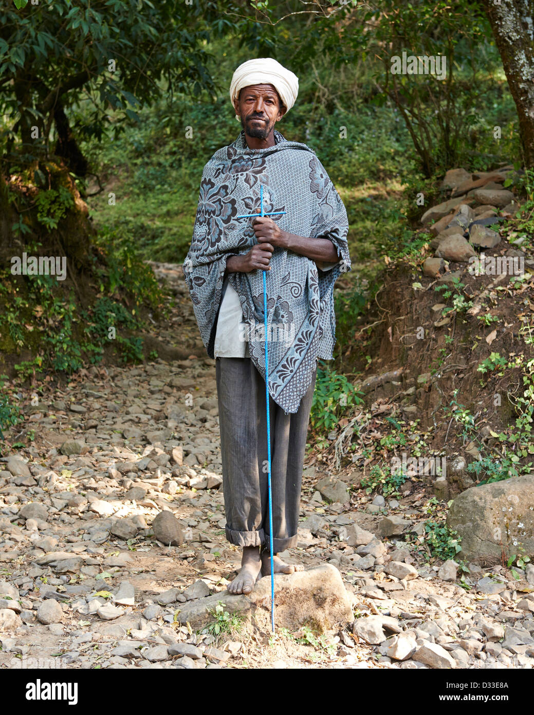 A elder local pilgrim man carrying a blue cross and standing in front ...