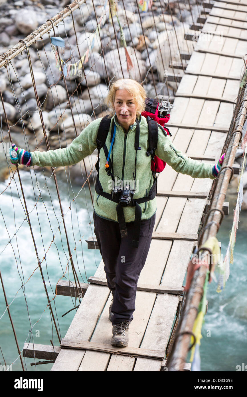 Trekkers crossing a suspension bridge crossing on the Annapurna Base ...