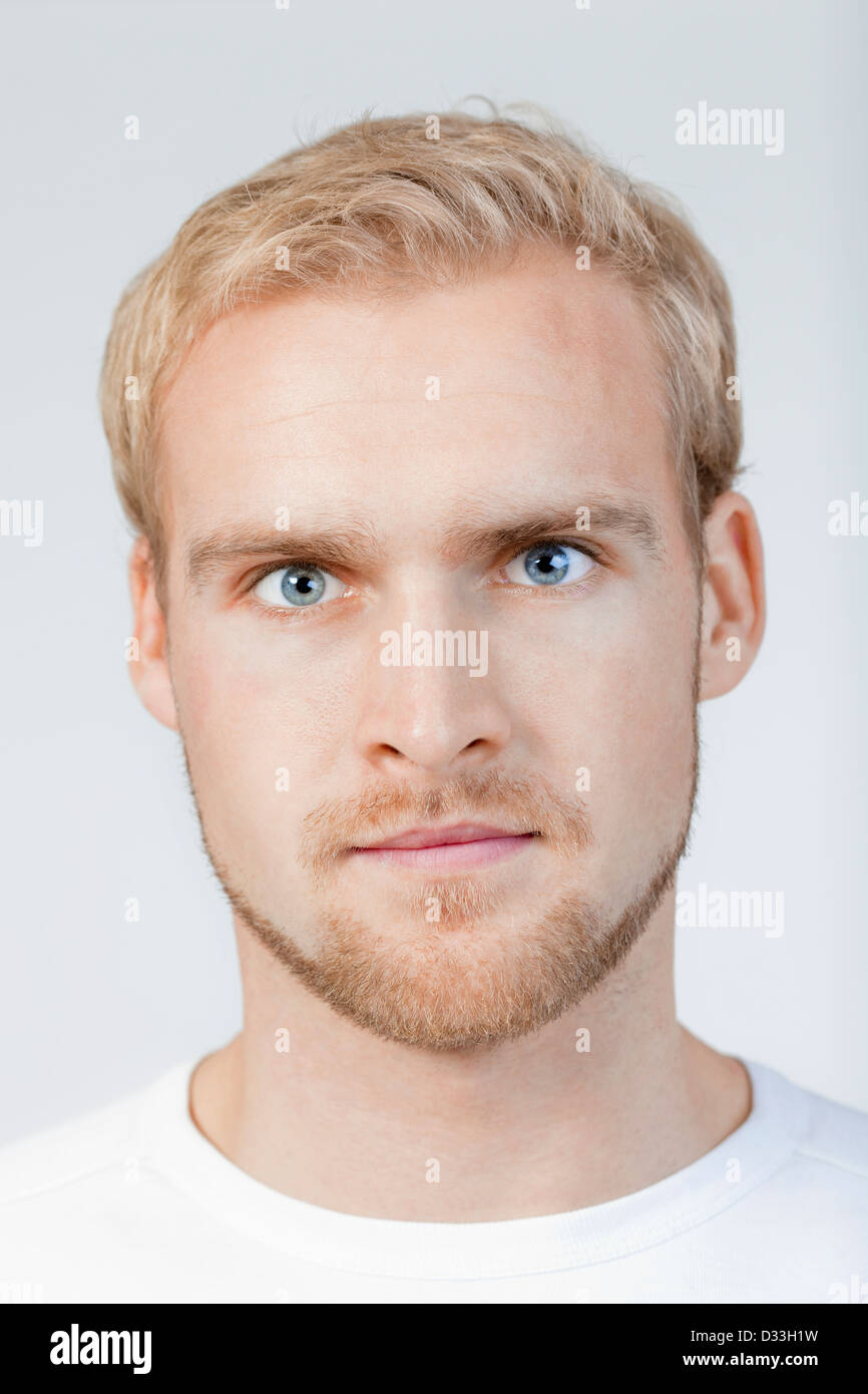 portrait of a young man with blond hair standing- isolated on light ...