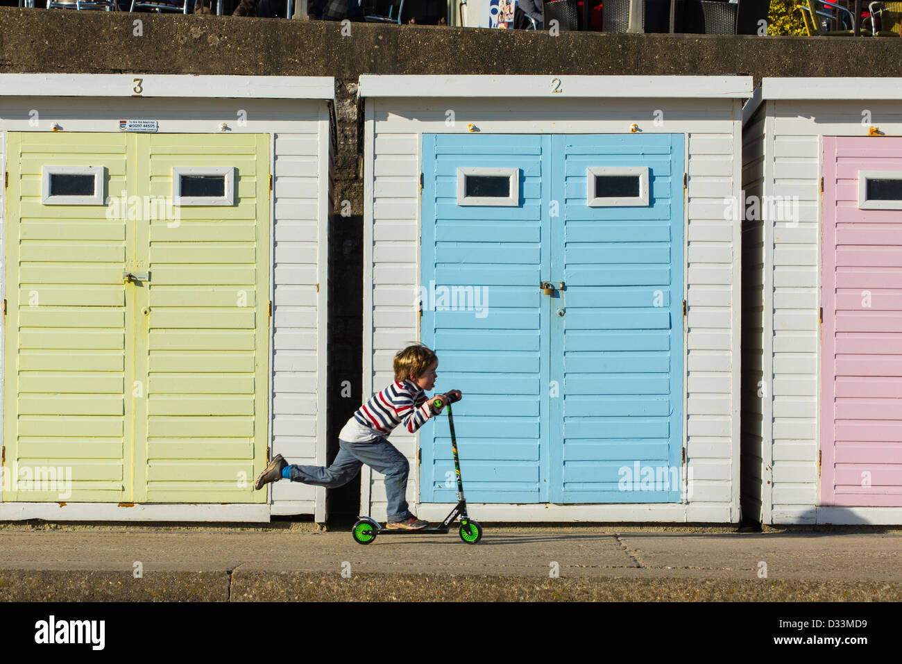 Child Scooting in front of some Beach huts, Lyme Regis, Dorset, England ...