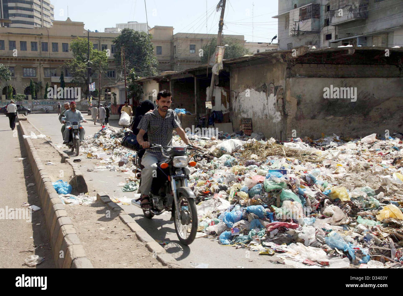 Karachi, Pakistan. 8th February 2013. Commuters pass through near huge ...