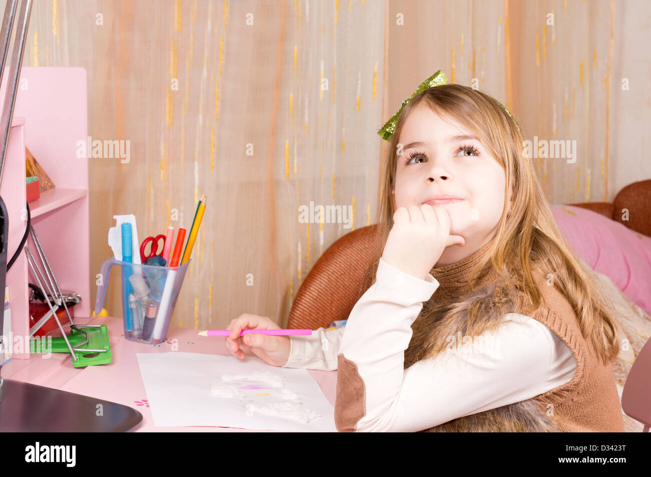 Smiling young girl daydreaming as she sits at her desk working looking ...