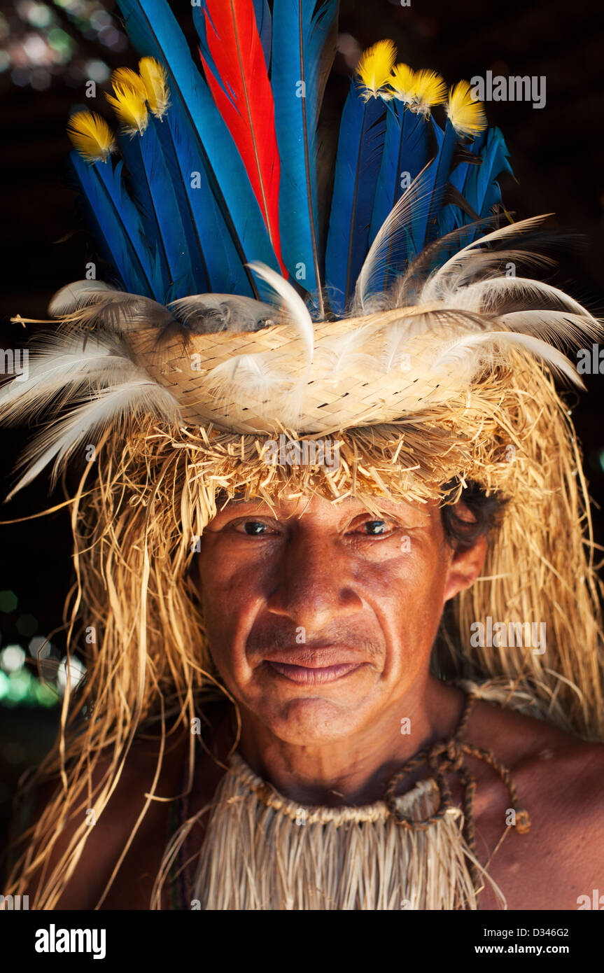 A Yagua man with traditional headdress of thatch and colorful feathers ...
