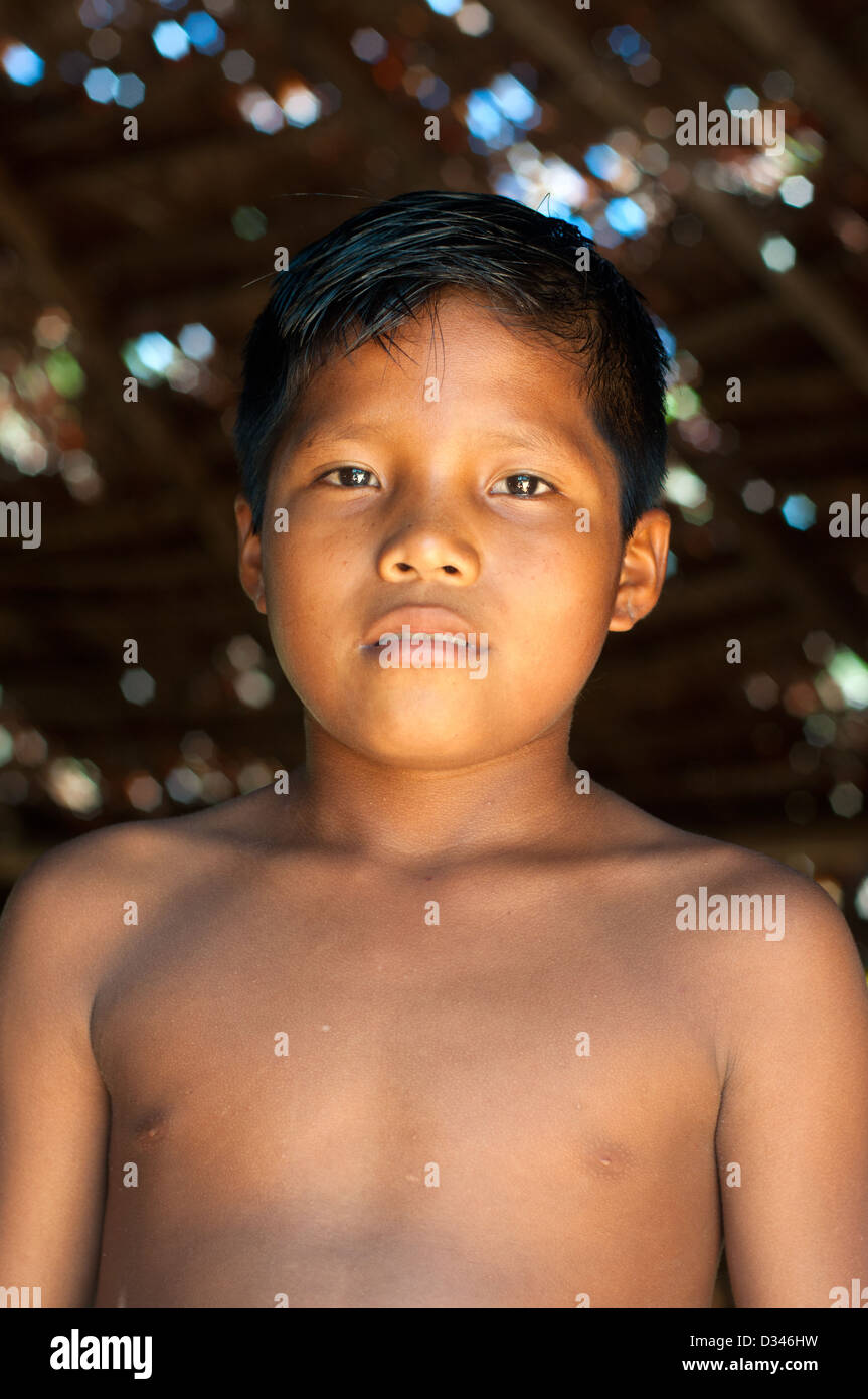 A Yagua young boy inside a maloca (traditional house with thatched roof ...