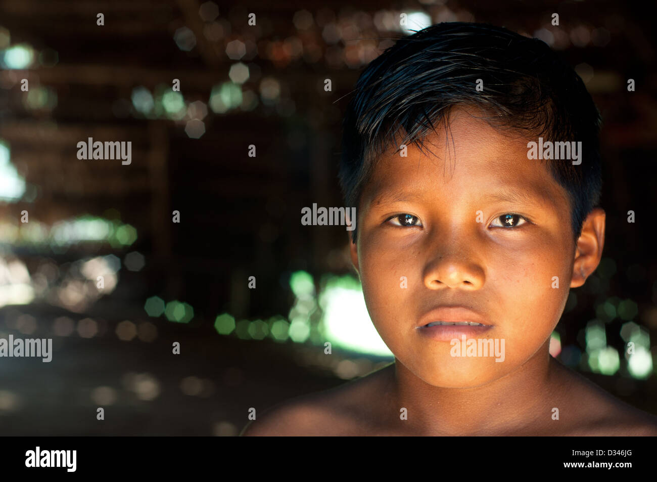 A Yagua young boy inside a maloca (traditional house with thatched roof ...