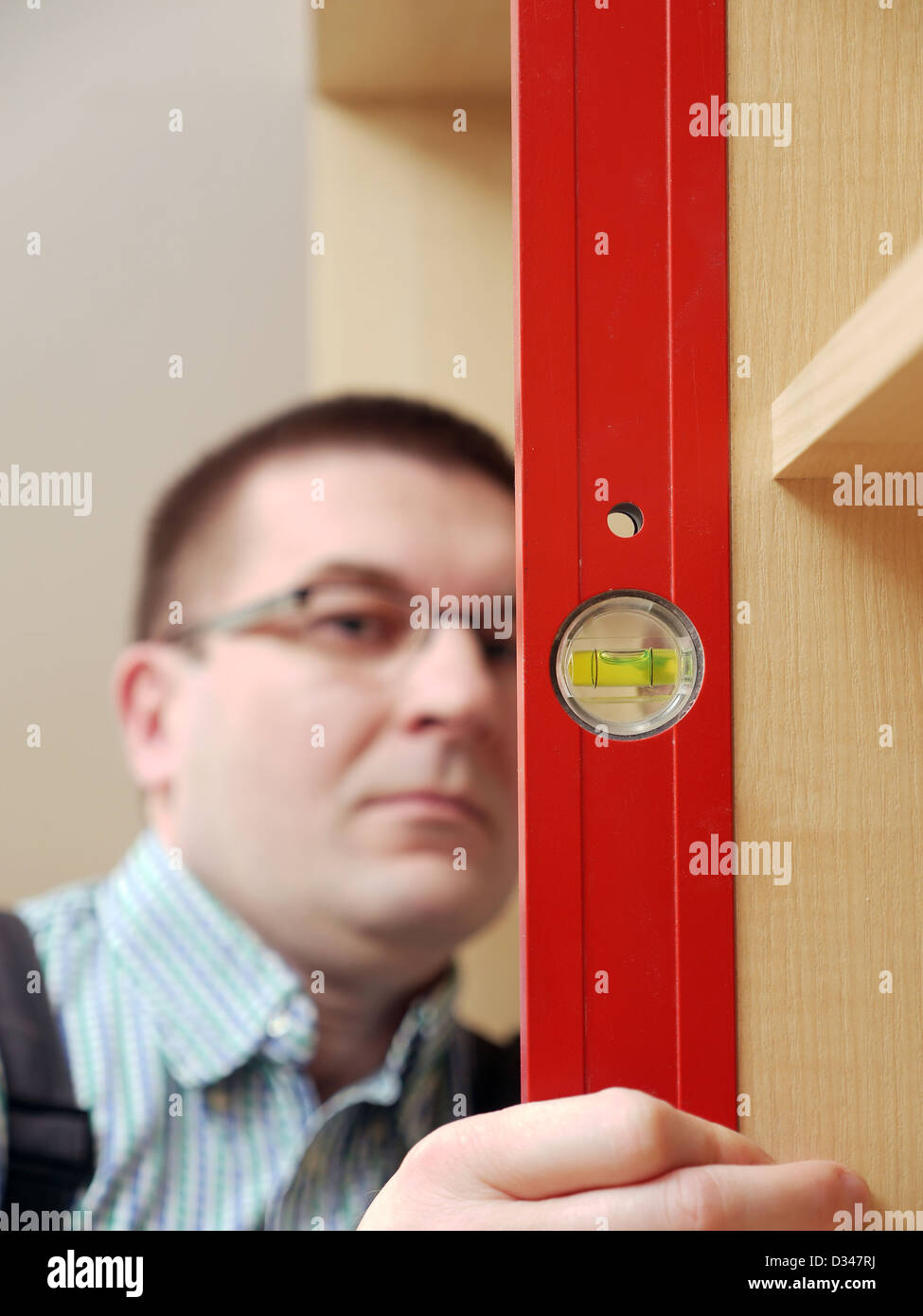 Carpenter using spirit level for leveling assembled wardrobe furniture ...