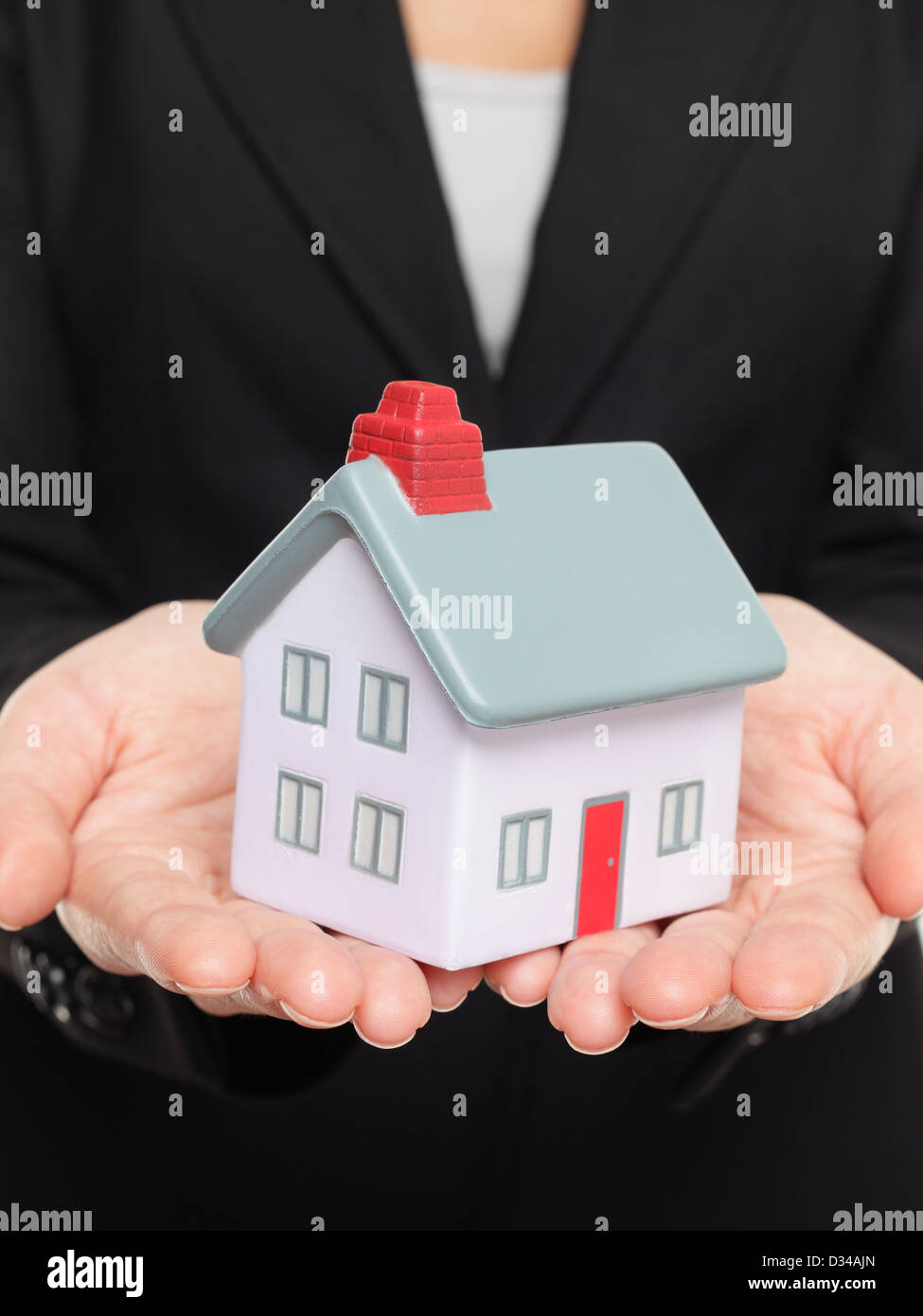 Closeup of female real estate agent showing mini house / home isolated ...