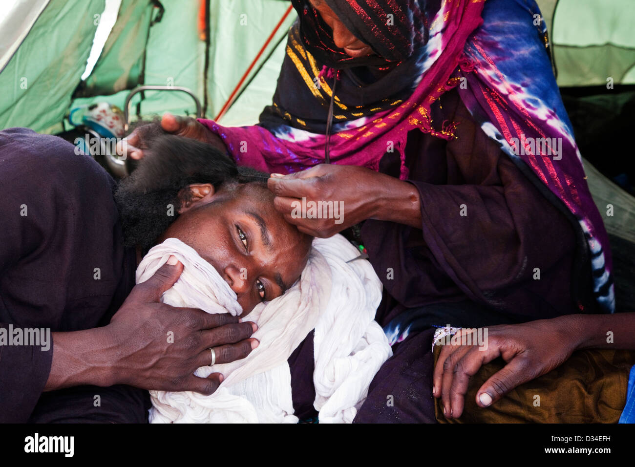 Wodaabe woman is combing a Wodaabe man's hair in preparation for ...