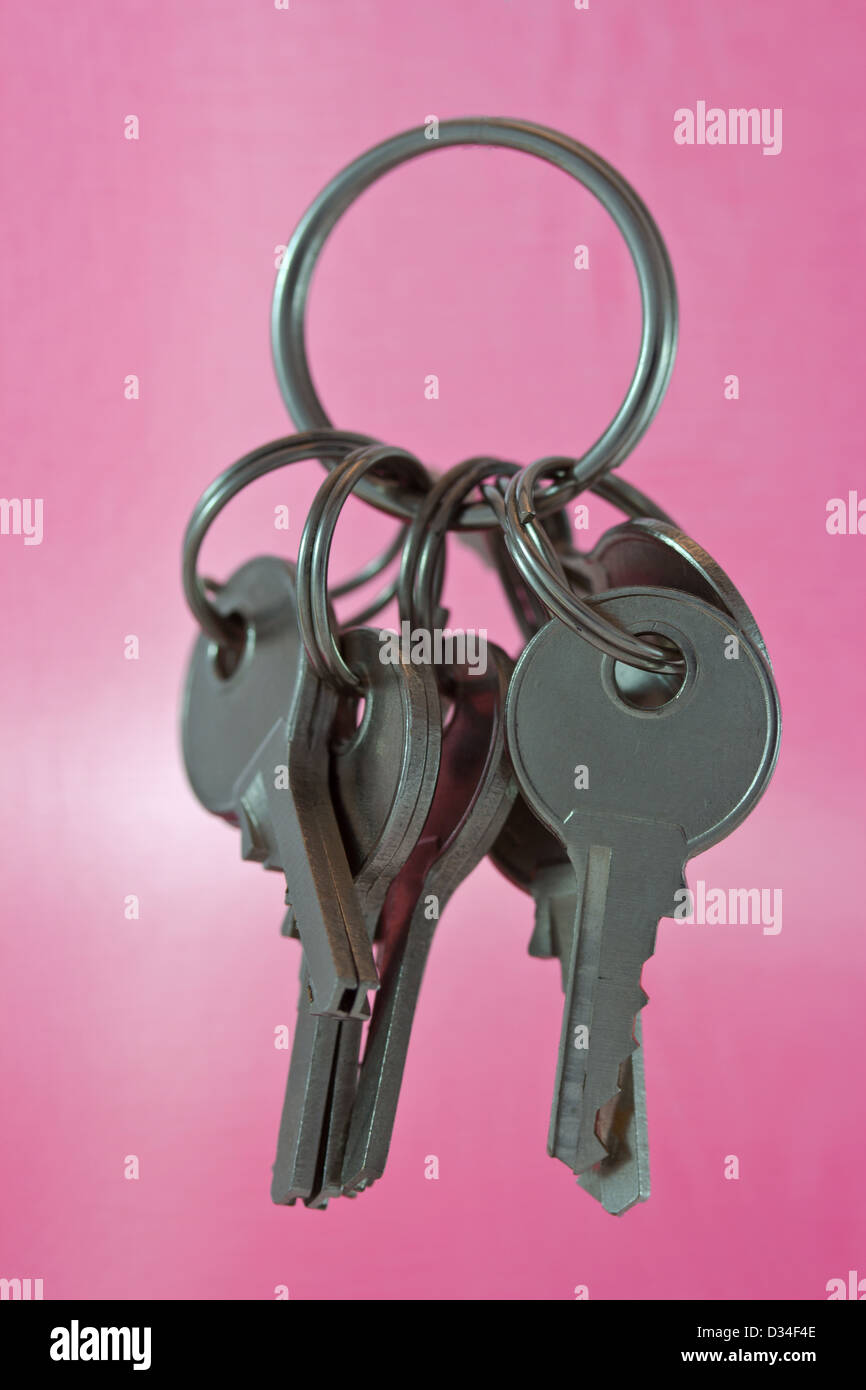Bunch of steel keys on key ring against pink background Stock Photo - Alamy