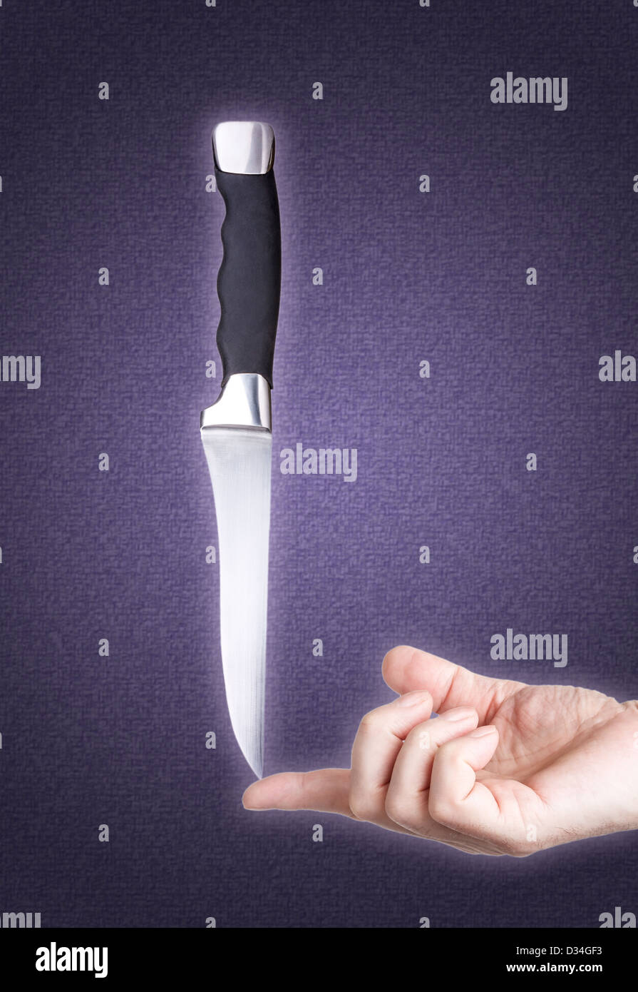 Magic chief steel knife balanced on the finger over purple textured ...