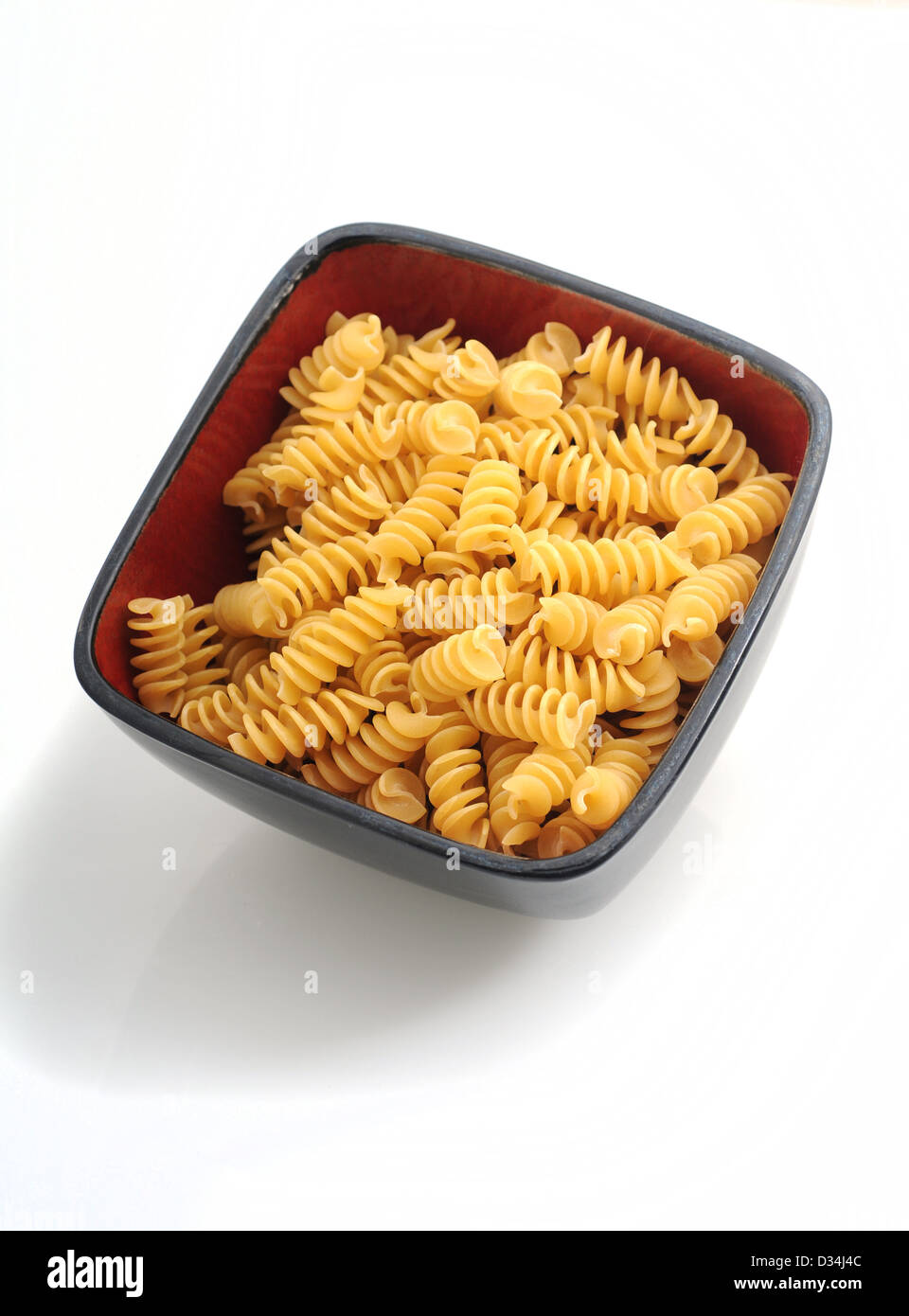 a bowl of rotelli pasta in red bowl on white background Stock Photo - Alamy