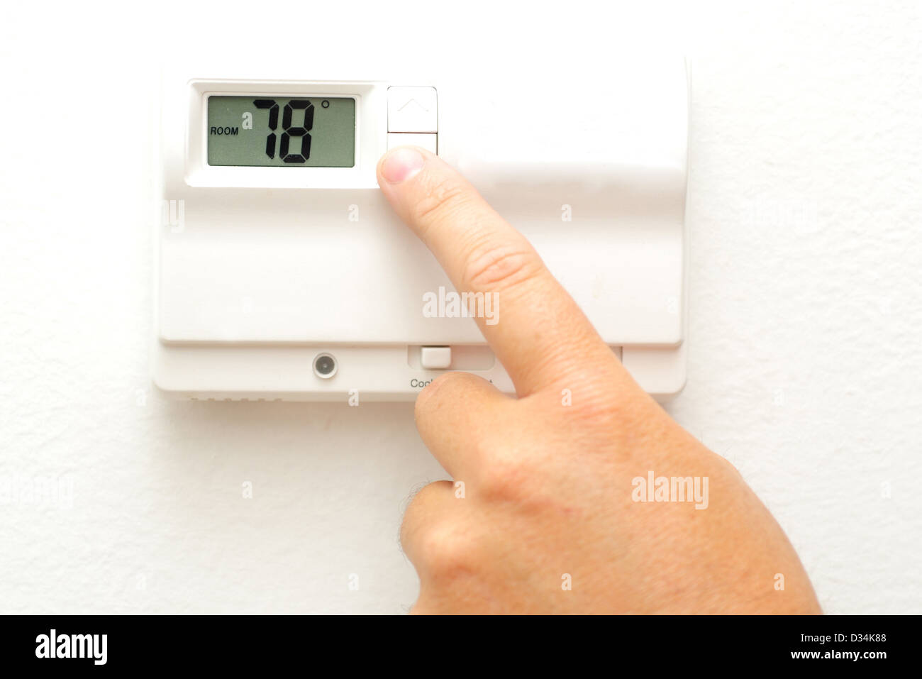 A hand turning down the thermostat for an energy savings concept Stock ...
