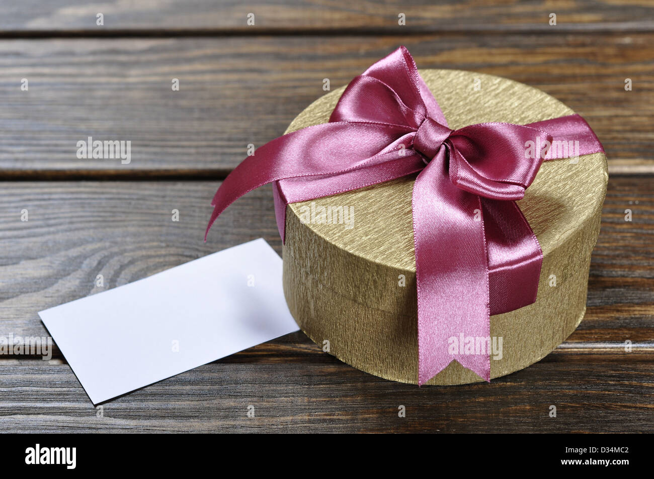 Golden gift box with pink ribbon on wooden background Stock Photo - Alamy