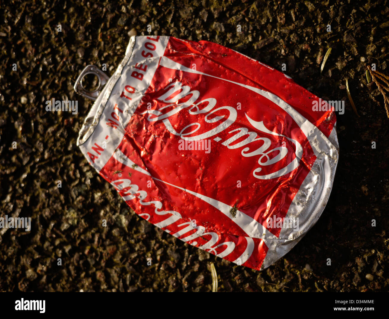 A crushed and discarded Coca-Cola can lies on a city street ...