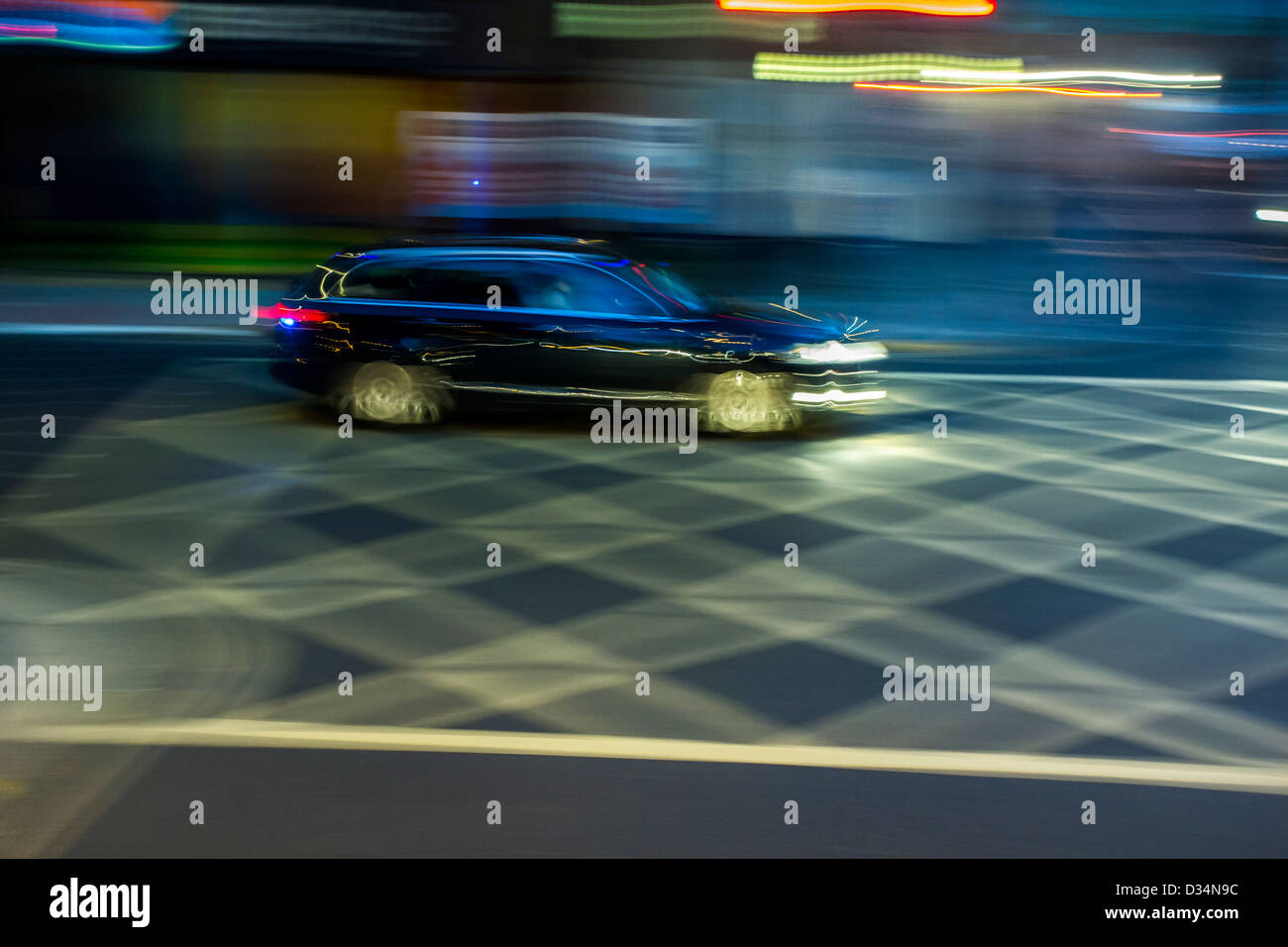 A modern automobile speeding through a city intersection at night - car ...