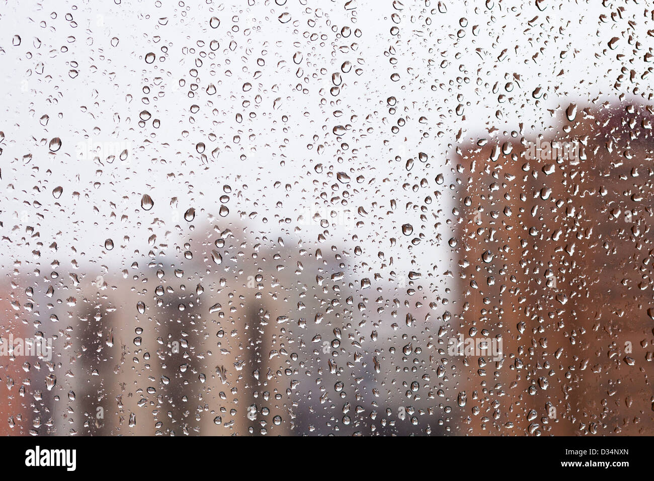 raindrops on home glass window with city buildings background Stock ...