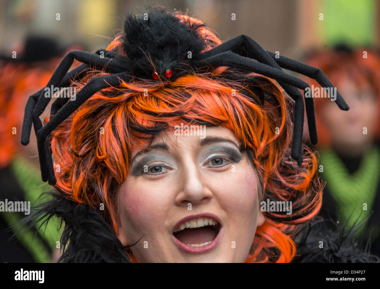 A carnival reveler with a spider on her head parties at the street ...