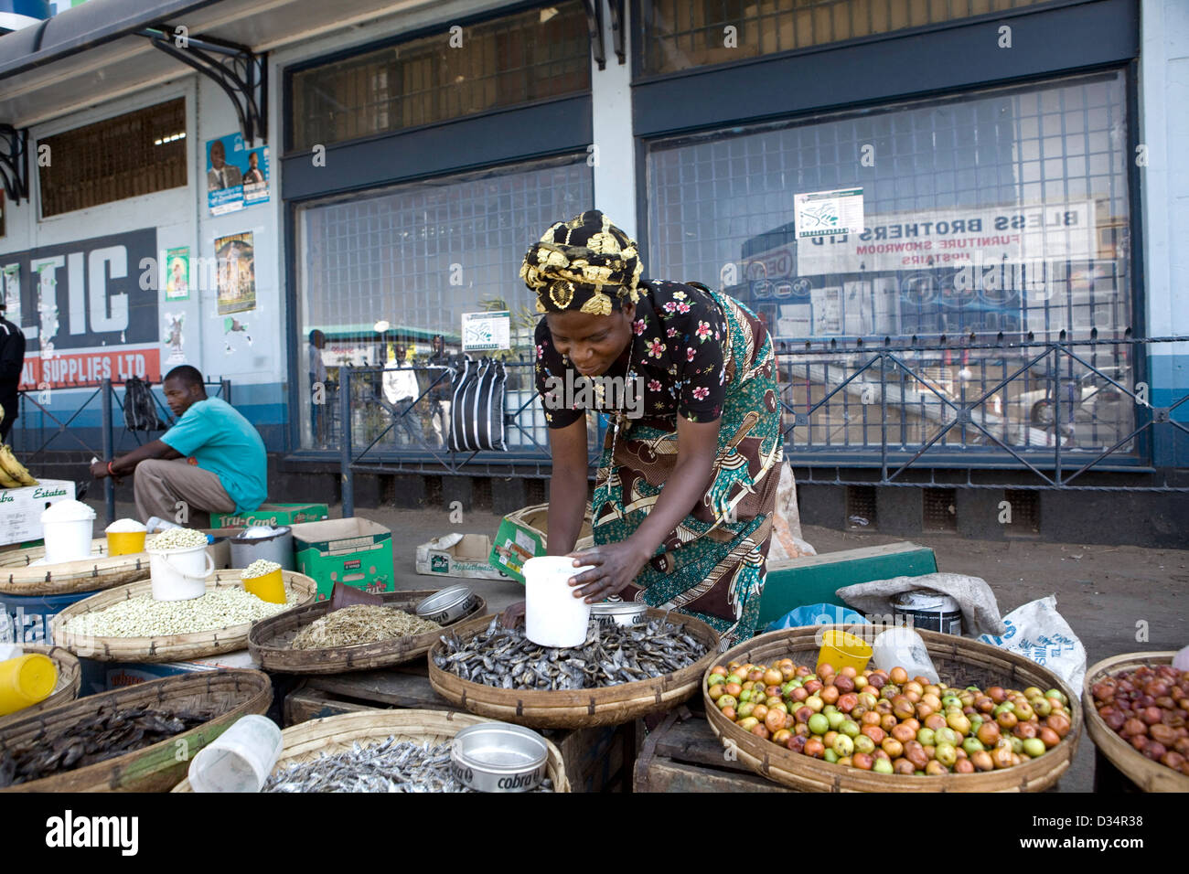 A woman packing dried fish in a small container ready to sell in Lusaka ...