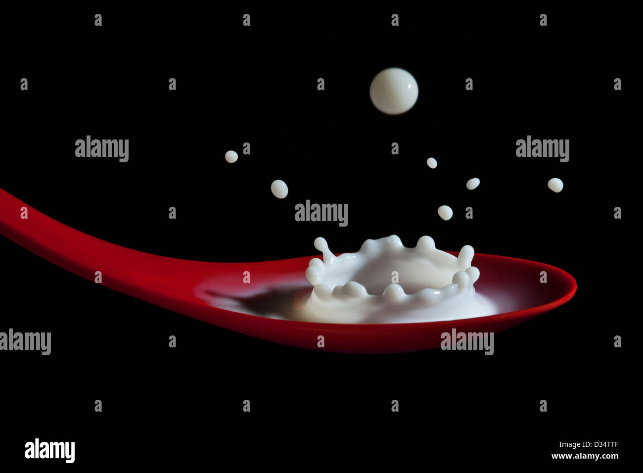 Milk splashing onto a red spoon Stock Photo - Alamy