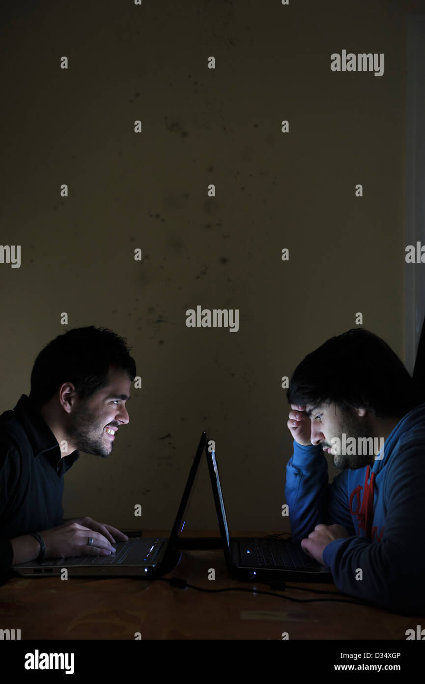 Two young men using laptop computers face to face Stock Photo - Alamy