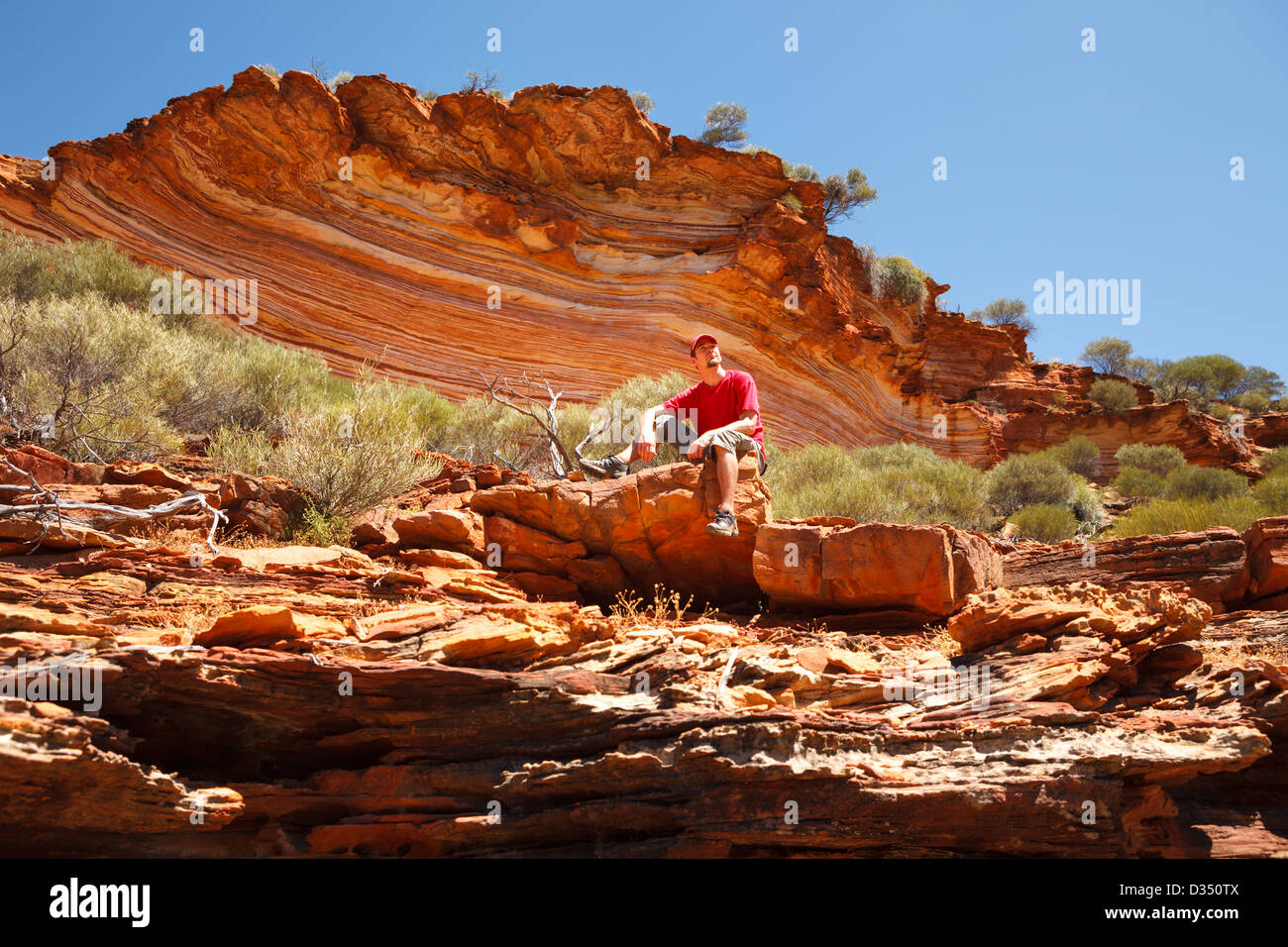 Man sitting bottom of colourful layered rock at loop walk, Kalbarri ...