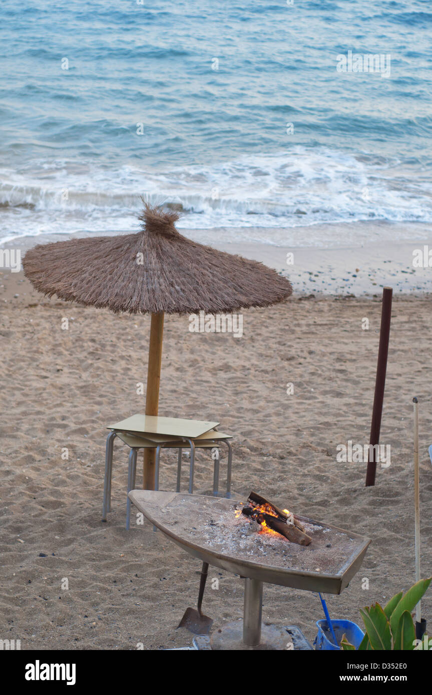 Umbrella on the beach and fireplace with fire Stock Photo - Alamy