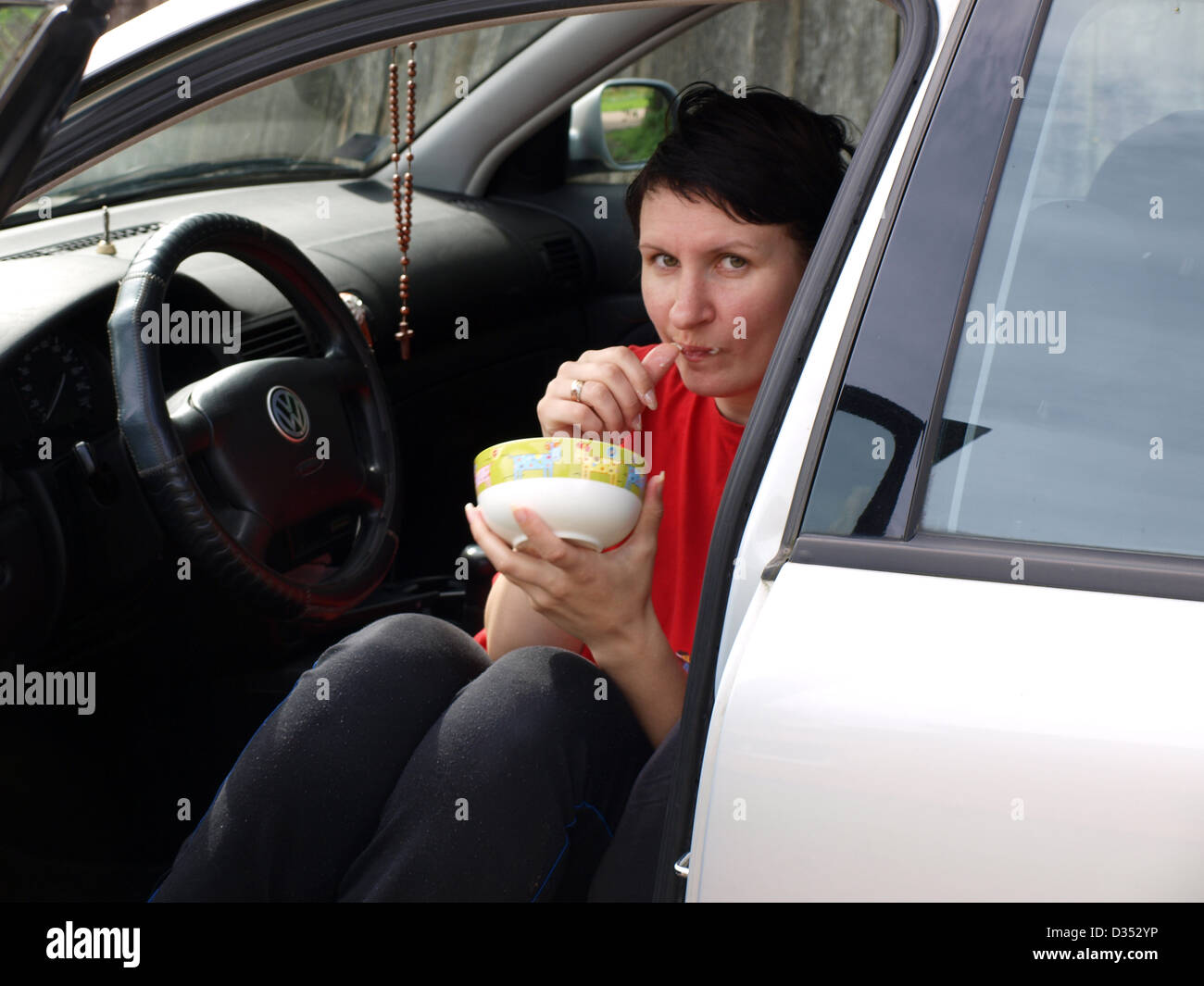 Young woman - driver sitting in car and eating from white bowl Stock ...