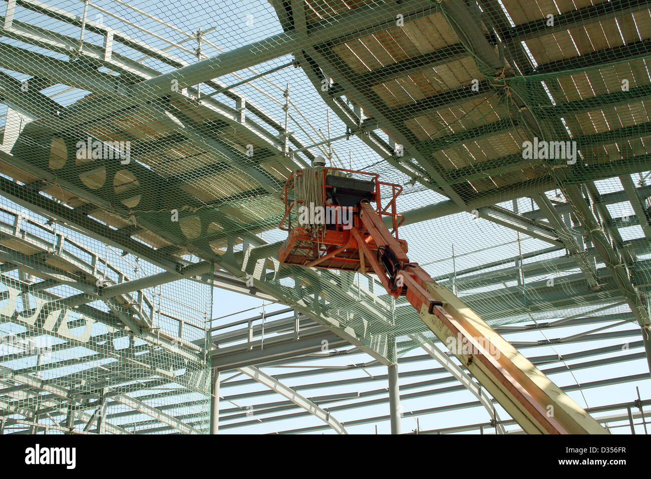 Man working at heights in a Cherry Picker erecting a safety net to ...