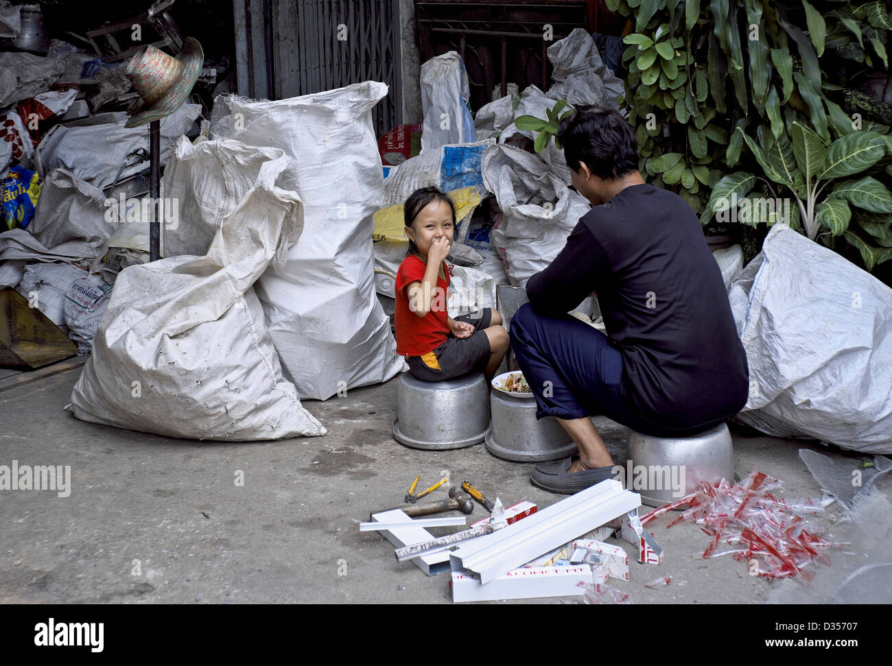 Thai child and father eating food amongst the garbage collection in a ...